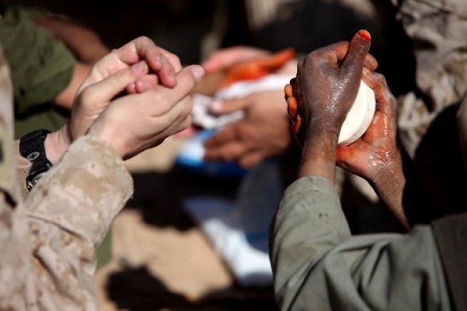 A female U.S. Marine teaches an Afghan child to wash his hands during a ...